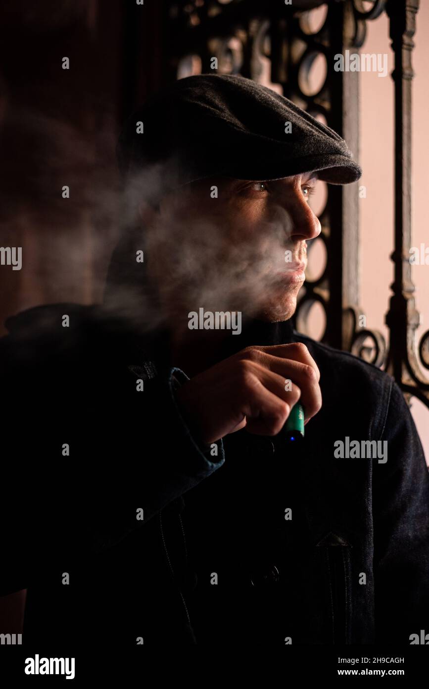 A man in a coat and cap walks around the city Stock Photo - Alamy