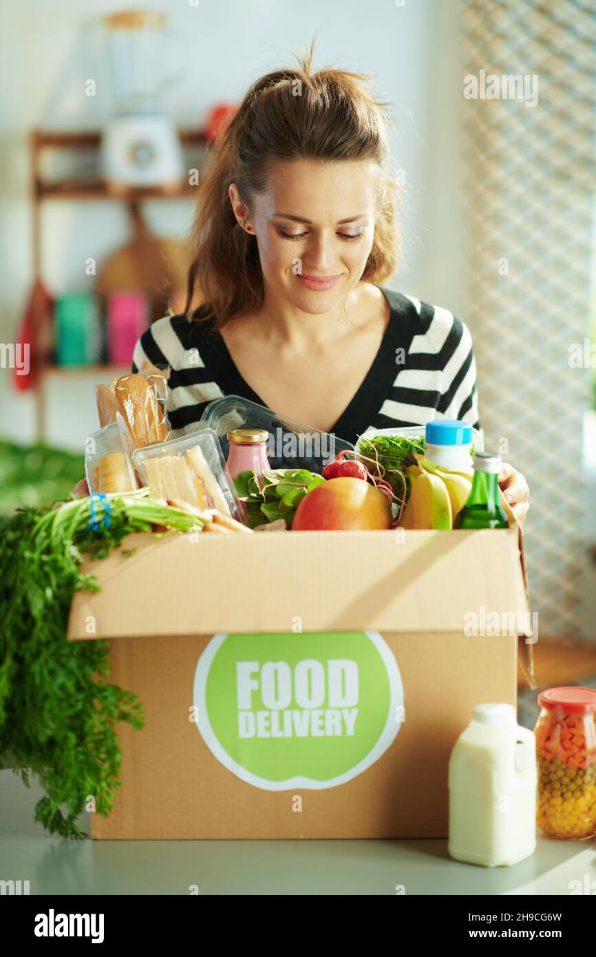 Food delivery. smiling young female with food box in the kitchen Stock ...