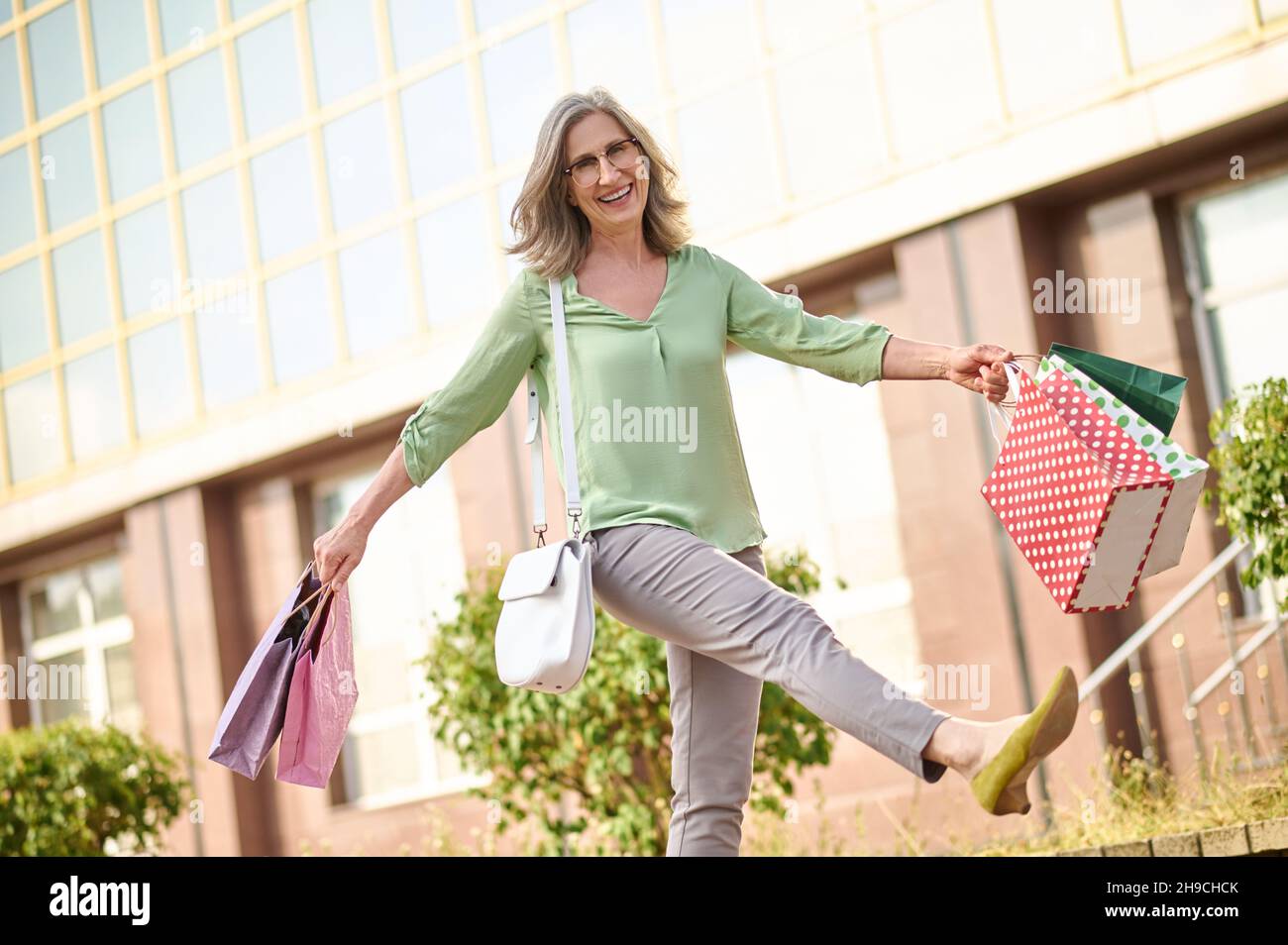 Cheerful adult woman waving hands with purchases Stock Photo - Alamy