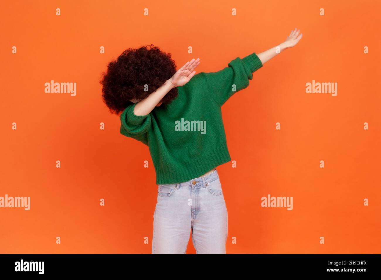 Woman with Afro hairstyle wearing green sweater showing dab dance ...