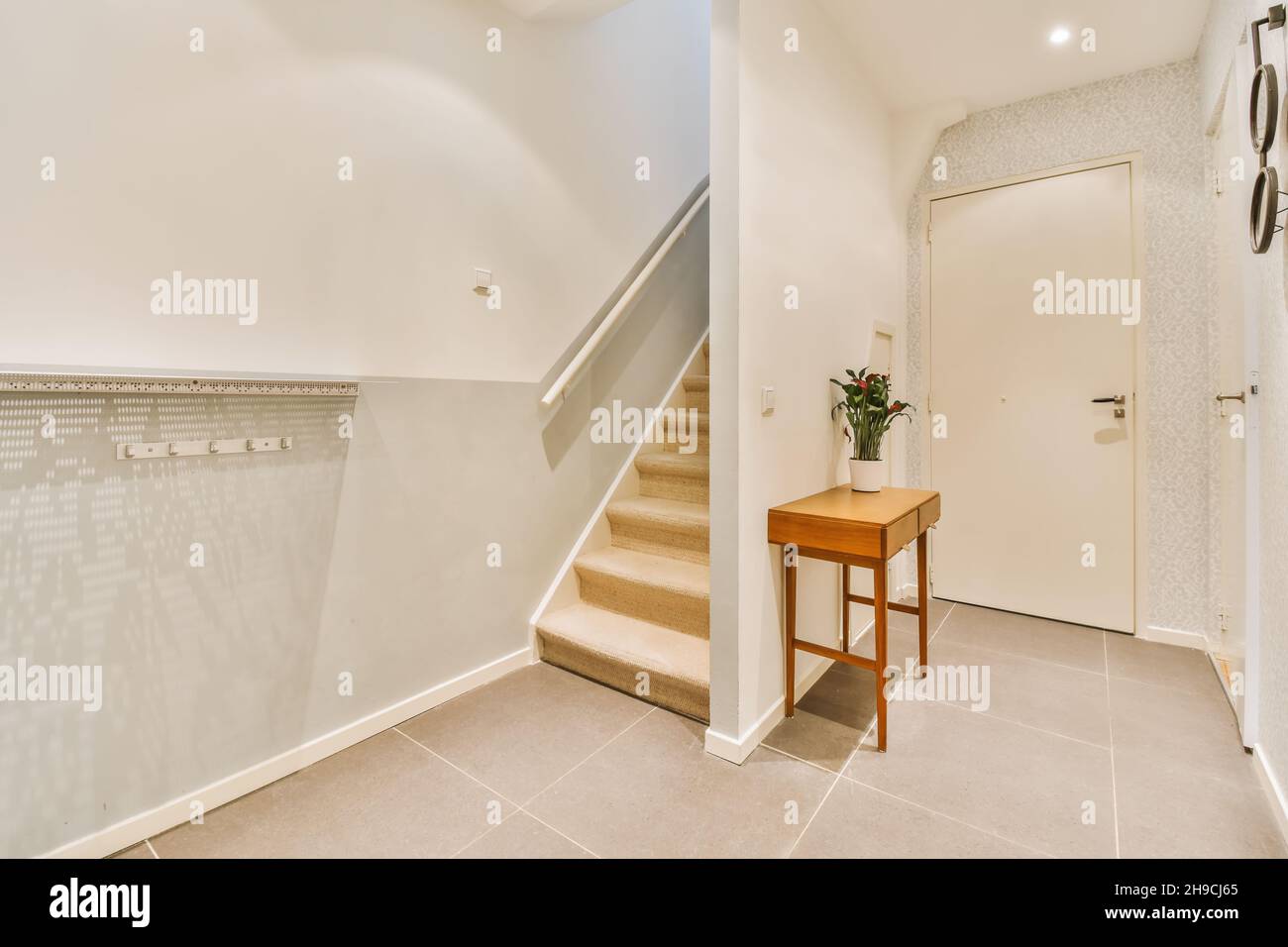 Wide entrance hall with a coat rack and a wooden cabinet on high legs ...
