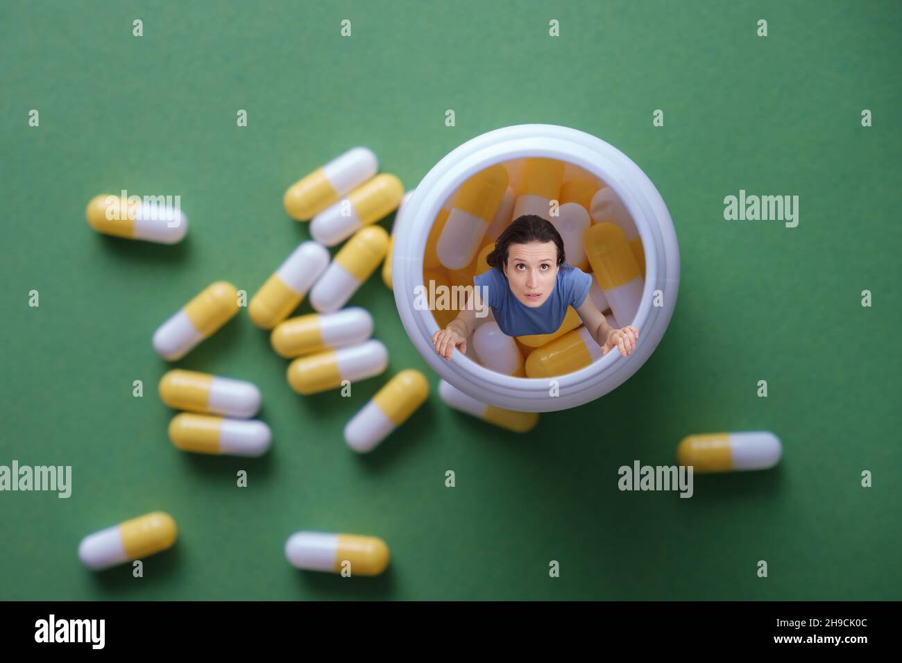 A woman gets out of a medicine jar. Medication capsules are scattered ...