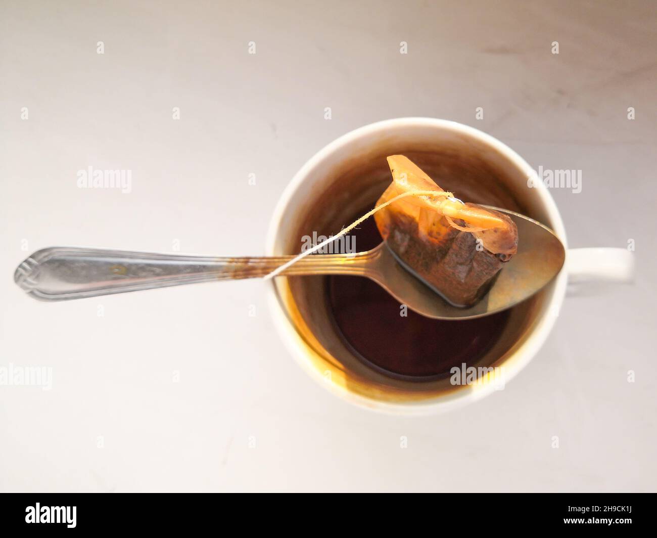 Wet used disposable tea bag on a metal spoon lying on a white dirty ...