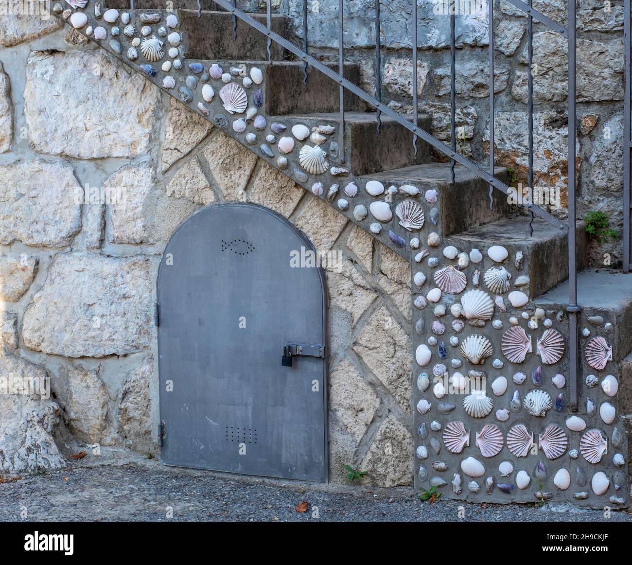 Old concrete stairs with railings decorated with seashells. Sea shells ...