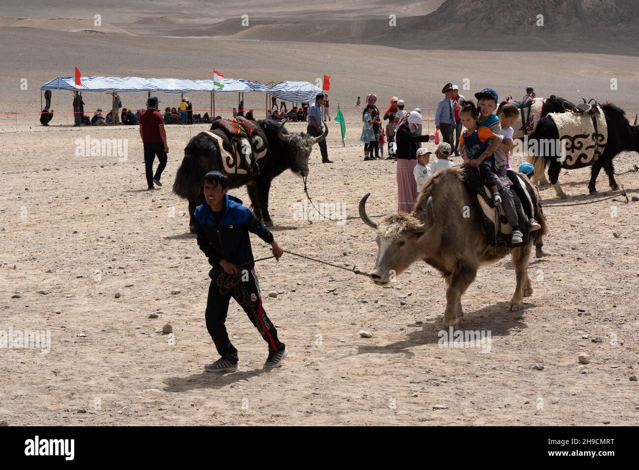 A youing boy on a yak being led by his father to the Murghab Horse ...