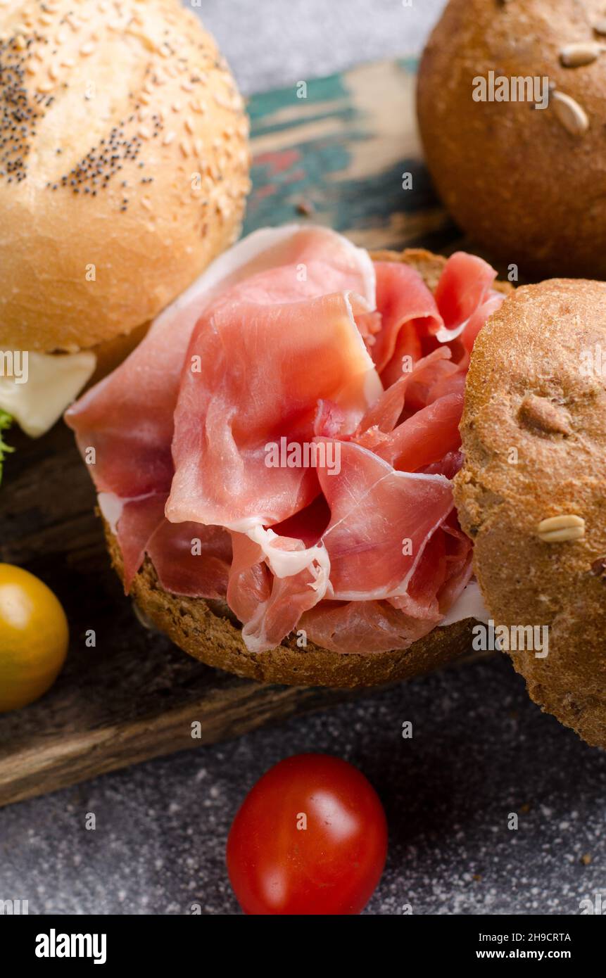 Delicious crispy burger bun with sliced ham on a vintage wooden cutting ...