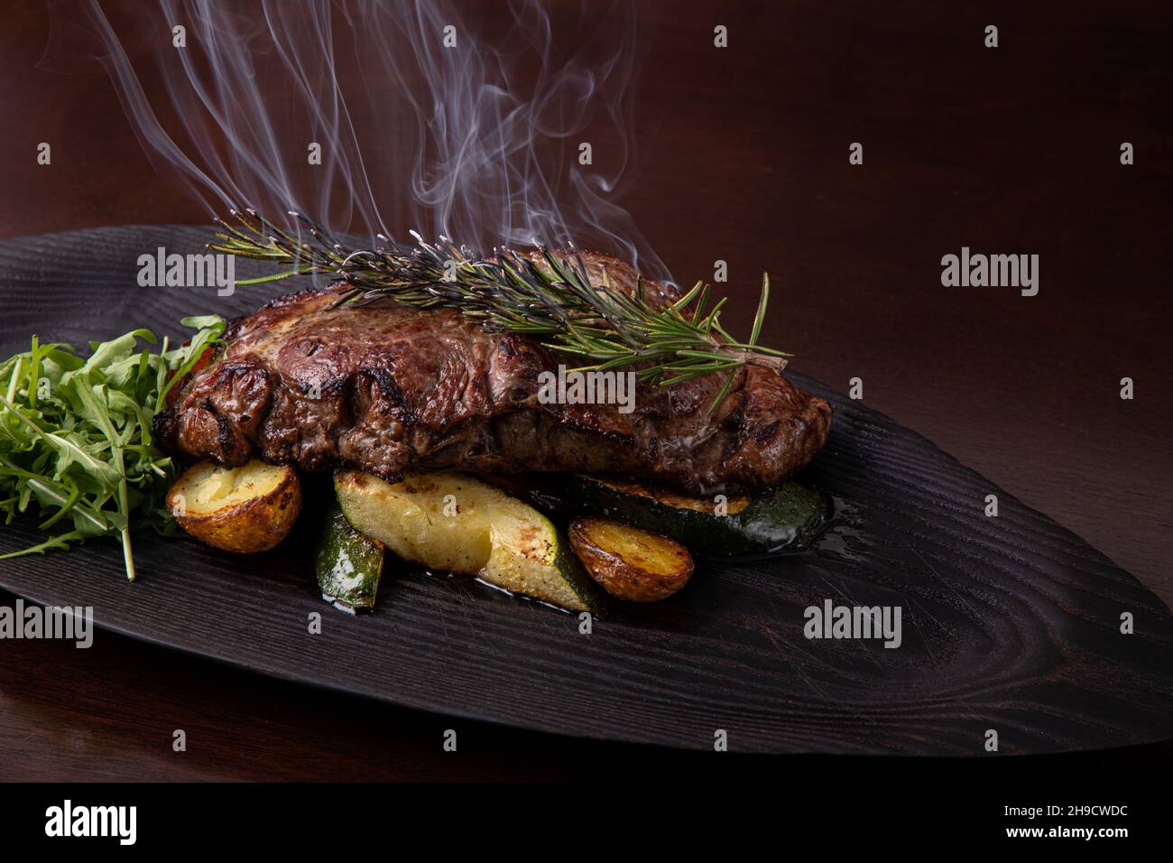 Grilled striploin steak on black dish. steak with fried potatoes and ...
