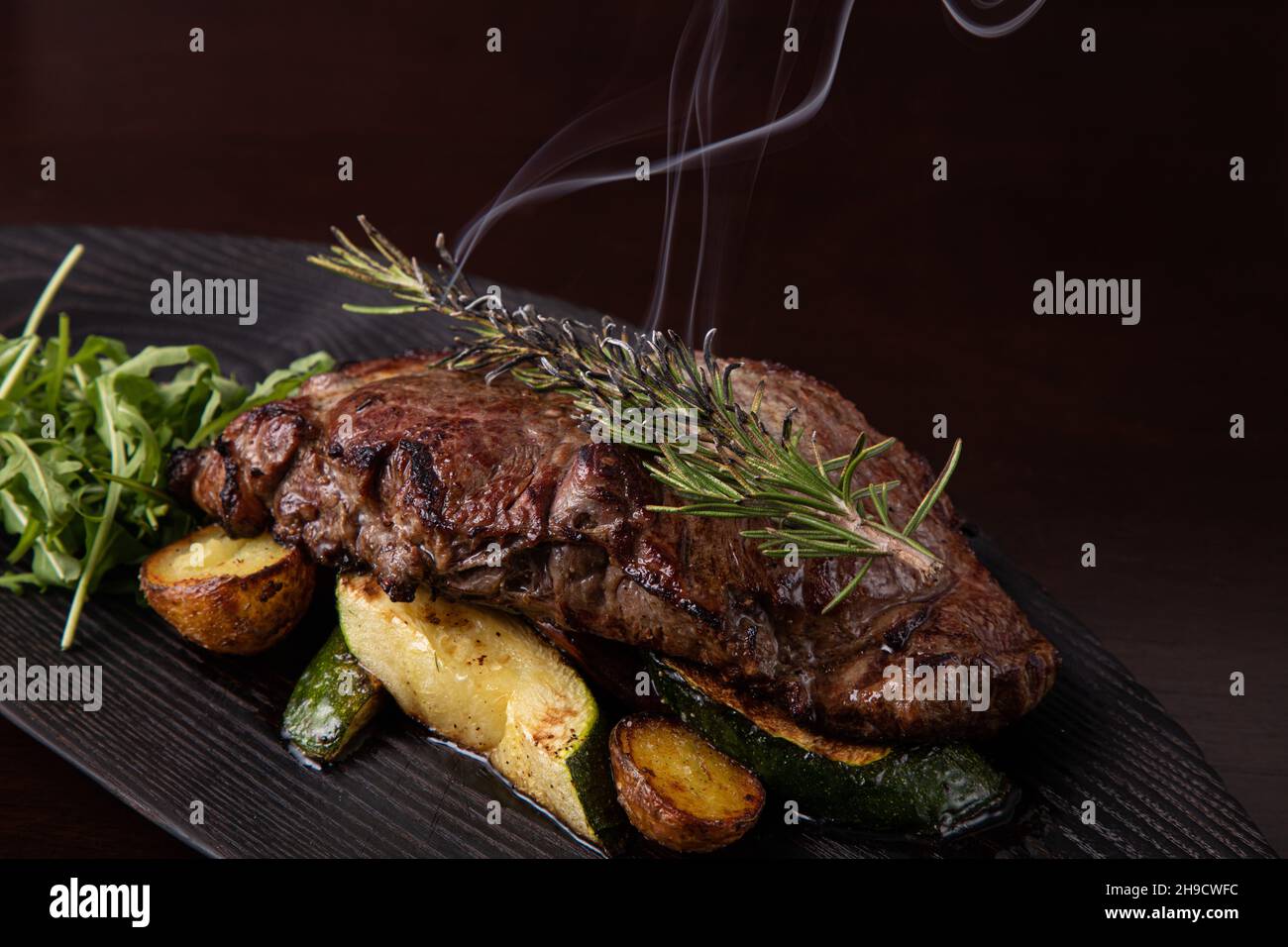 Grilled striploin steak on black dish. steak with fried potatoes and ...