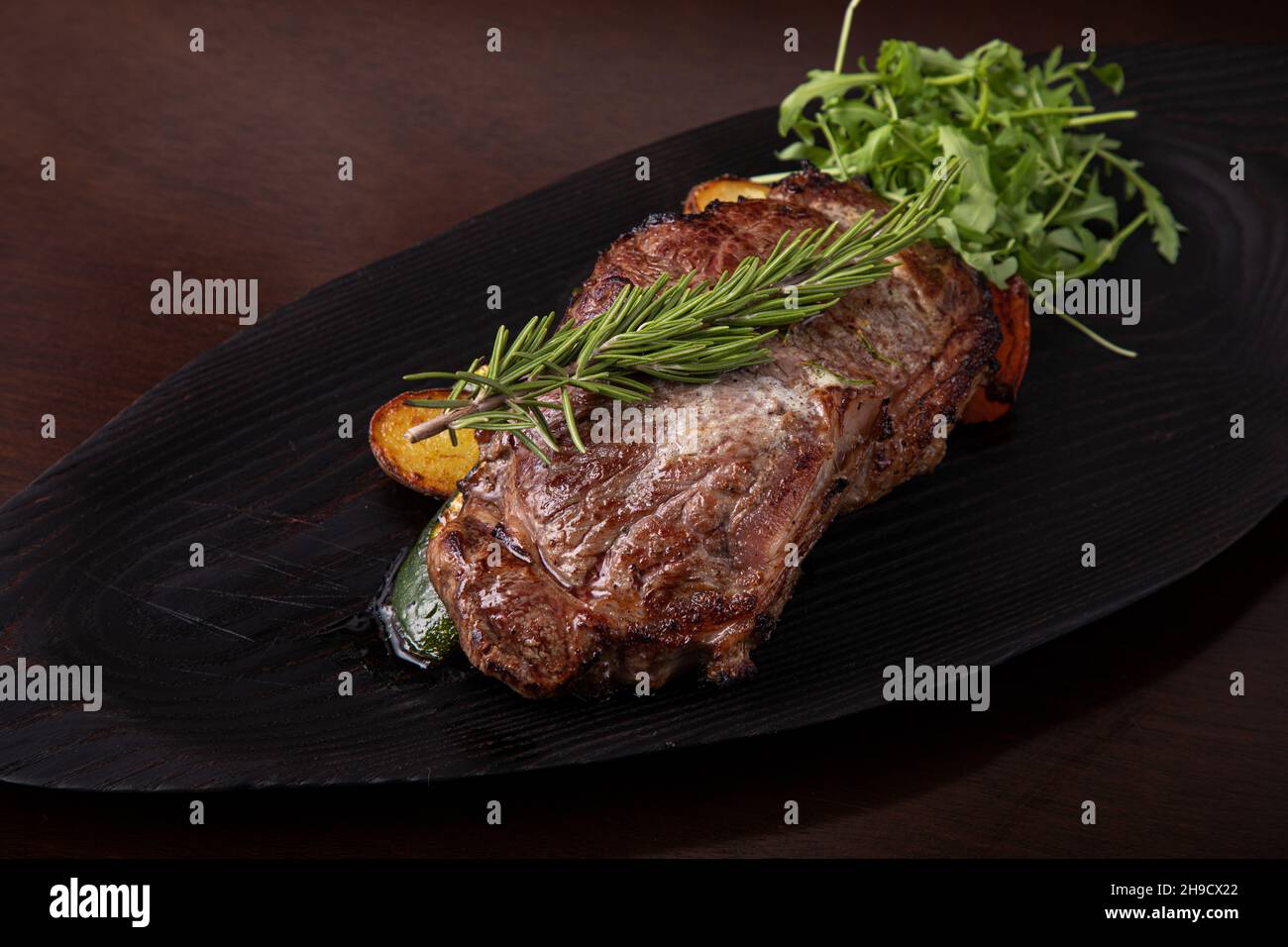 Grilled striploin steak on black dish. steak with fried potatoes and ...