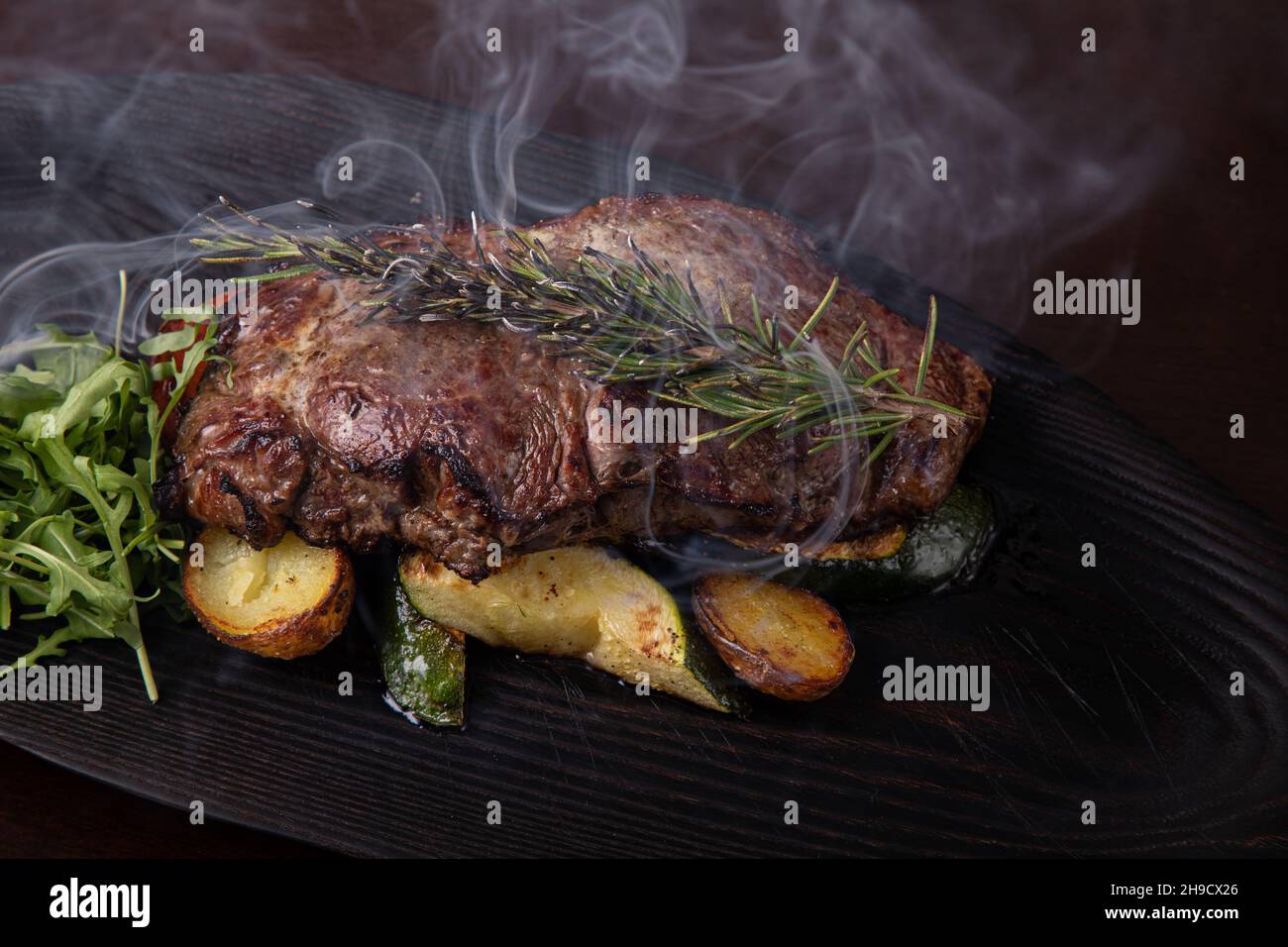 Grilled striploin steak on black dish. steak with fried potatoes and ...