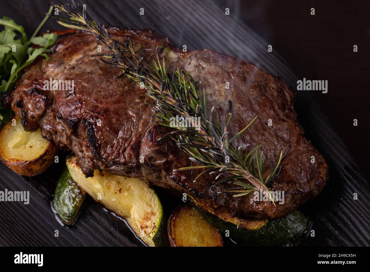 Grilled striploin steak on black dish. steak with fried potatoes and ...