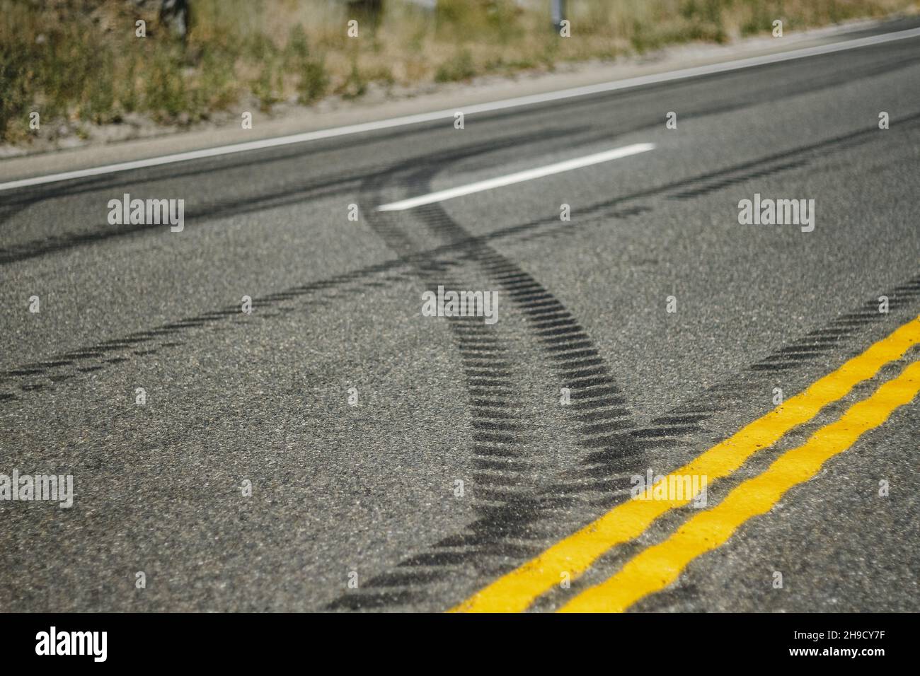 Empty asphalt road with wheel trails and yellow lines Stock Photo - Alamy