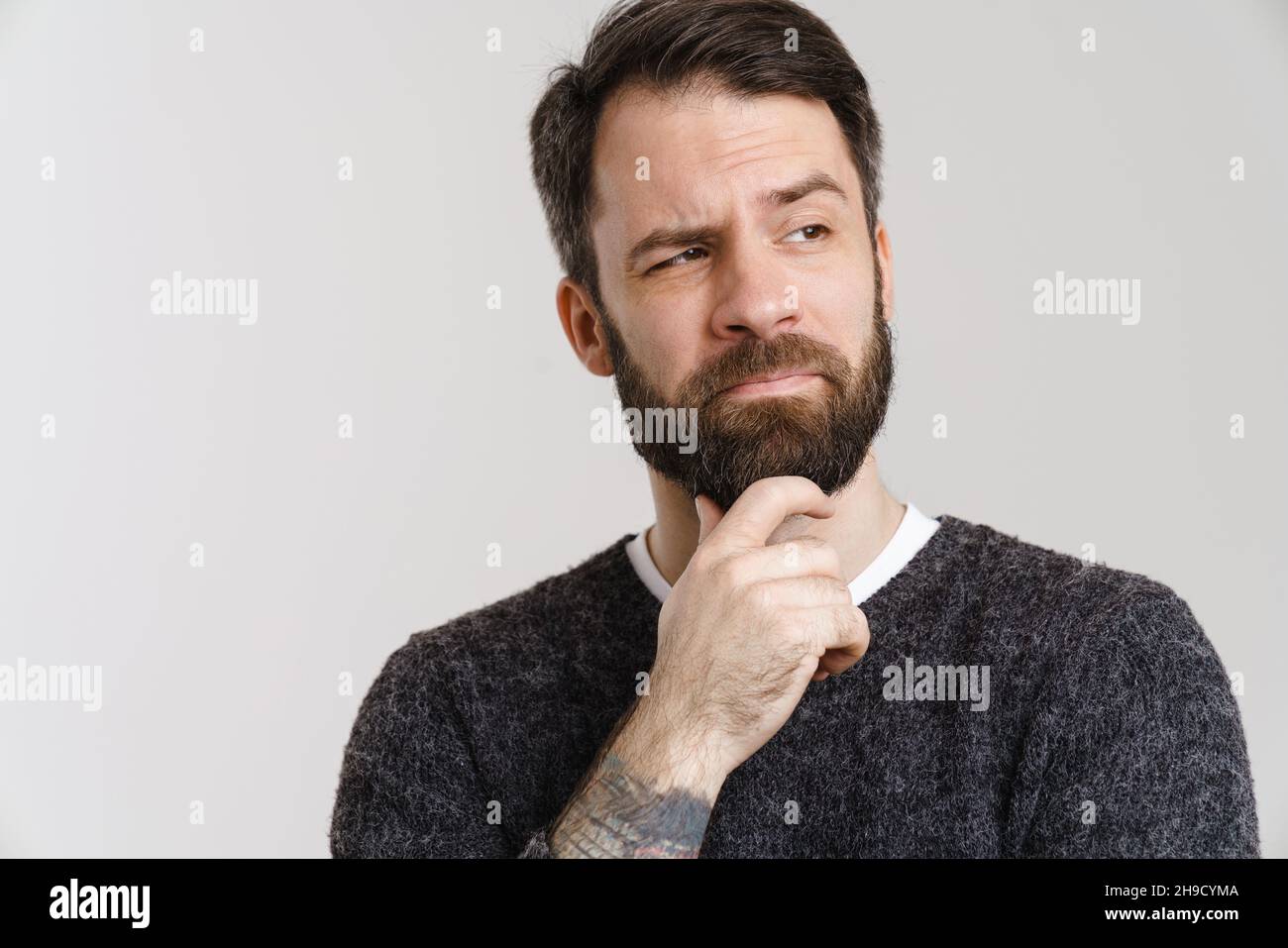 White puzzled man with beard posing and looking aside isolated over ...