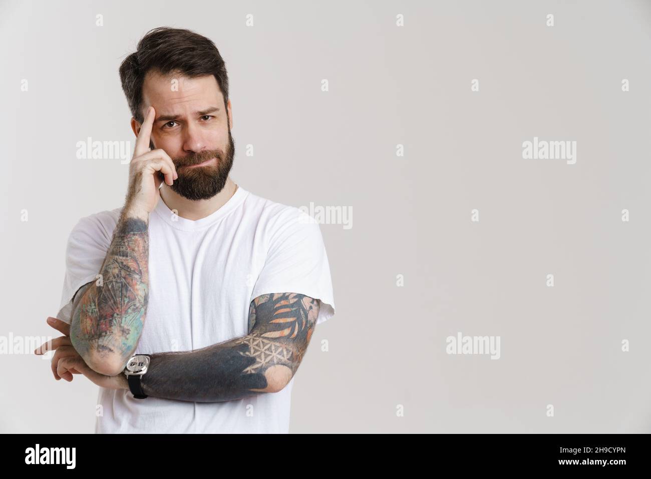 Bearded puzzled man touching his forehead and looking at camera ...