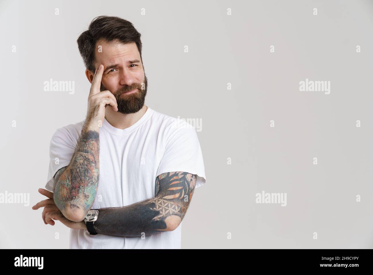 Bearded puzzled man touching his forehead and looking at camera ...