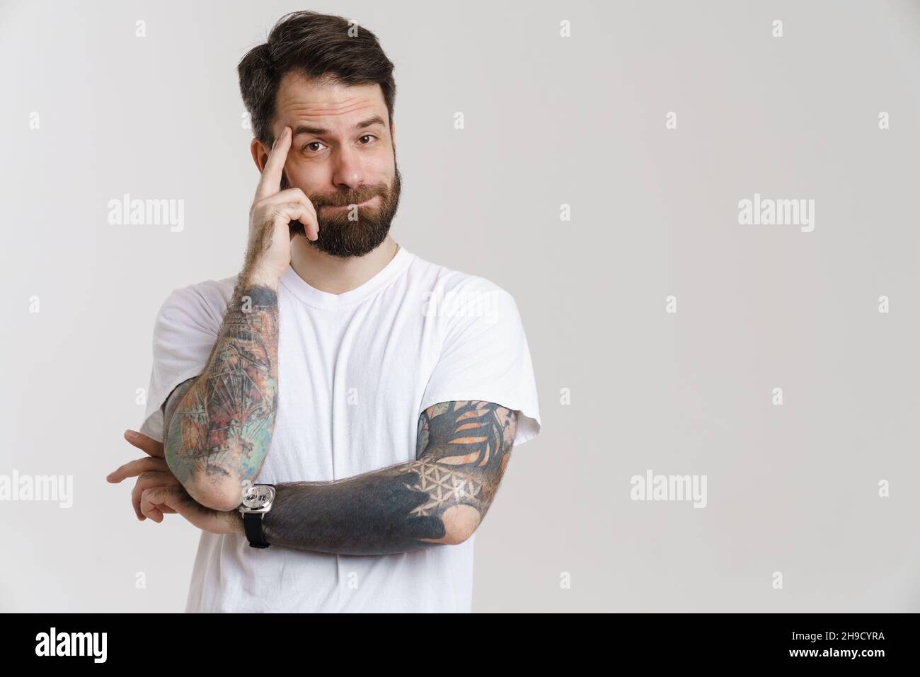 Bearded puzzled man touching his forehead and looking at camera ...