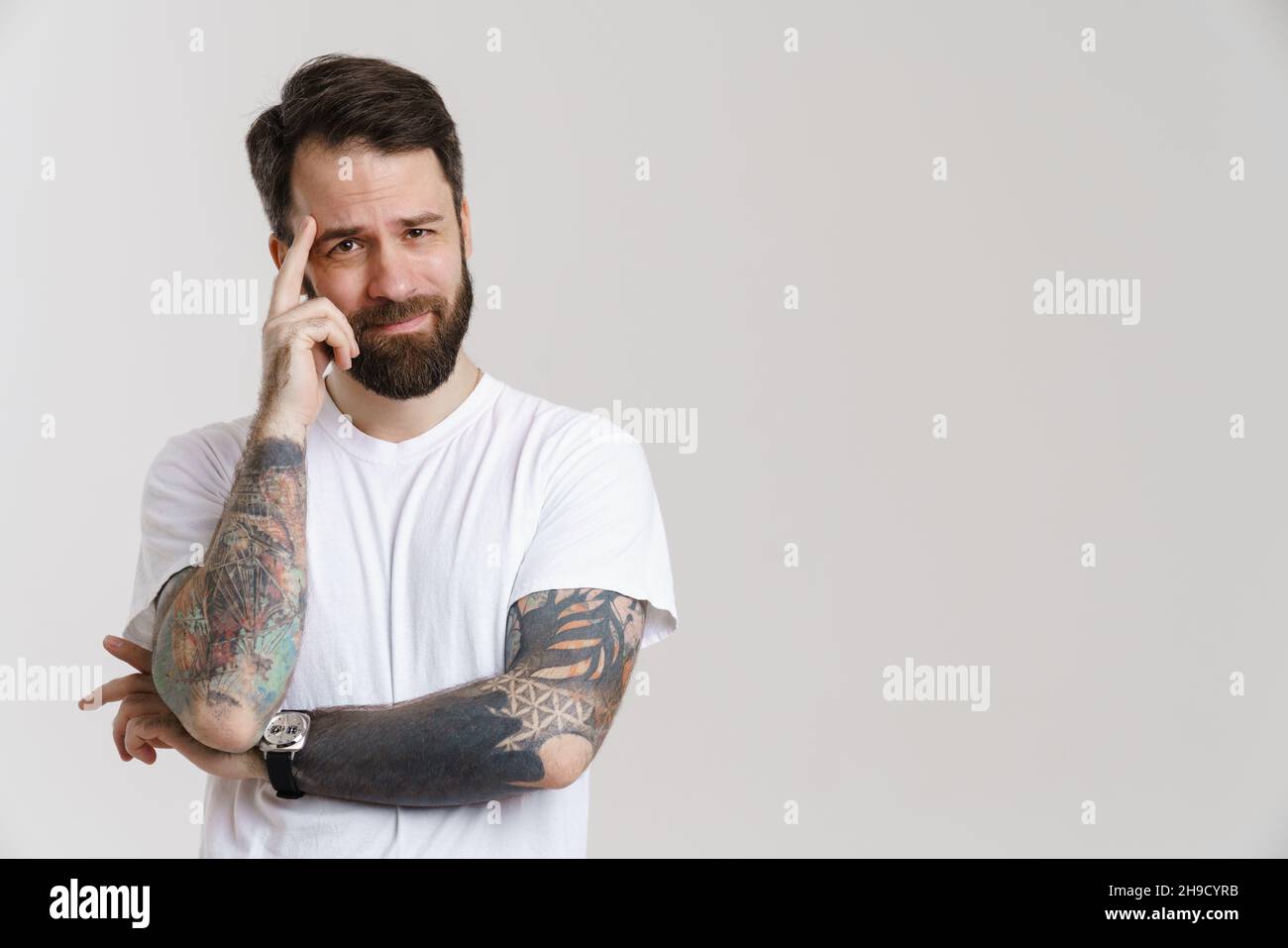 Bearded puzzled man touching his forehead and looking at camera ...