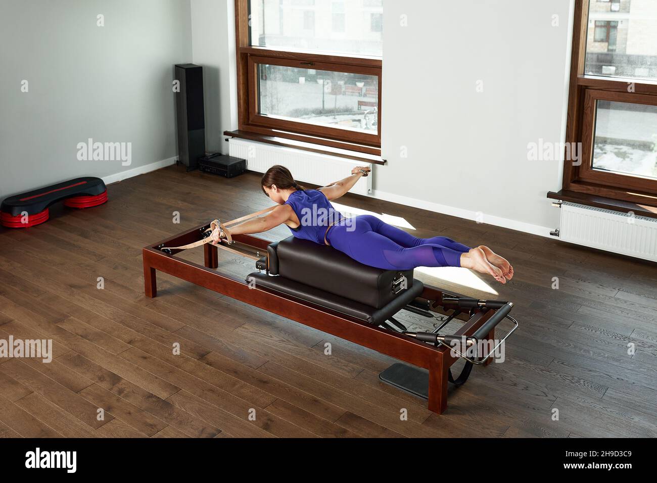 The instructor does exercises on the reformer, a beautiful girl trains ...