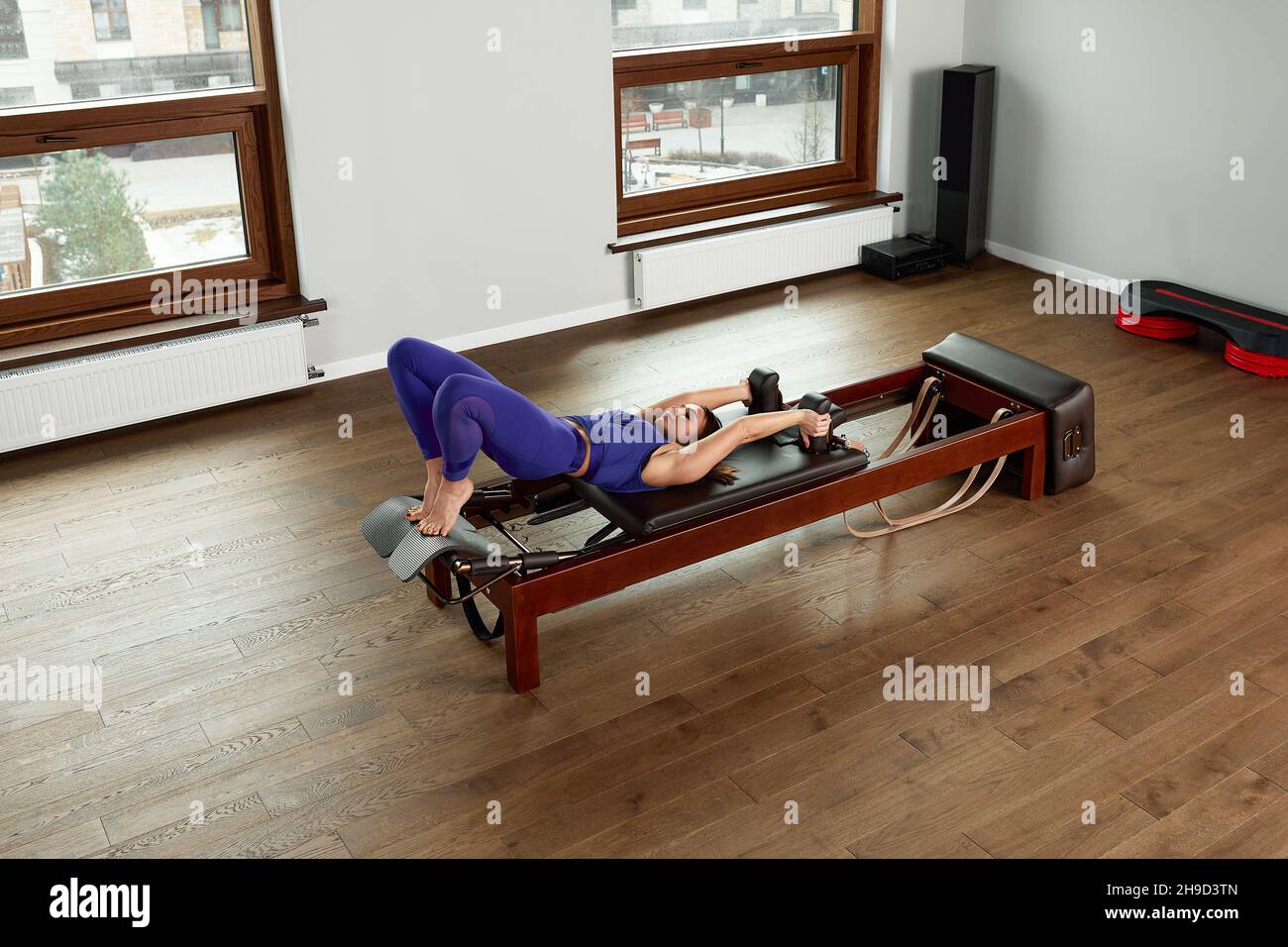 The instructor does exercises on the reformer, a beautiful girl trains ...