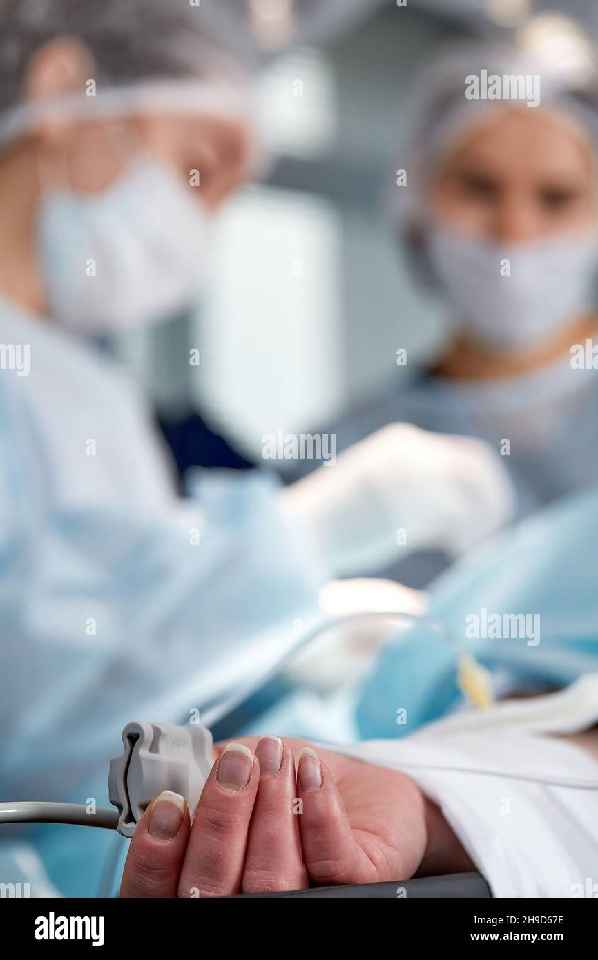 The patient's hand is under the IV with a pulse oximeter on the finger ...