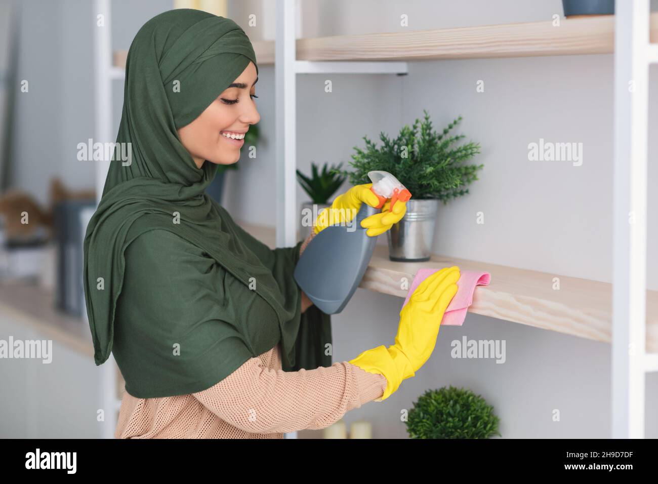Muslim young woman cleaning shelves with detergent at home Stock Photo ...