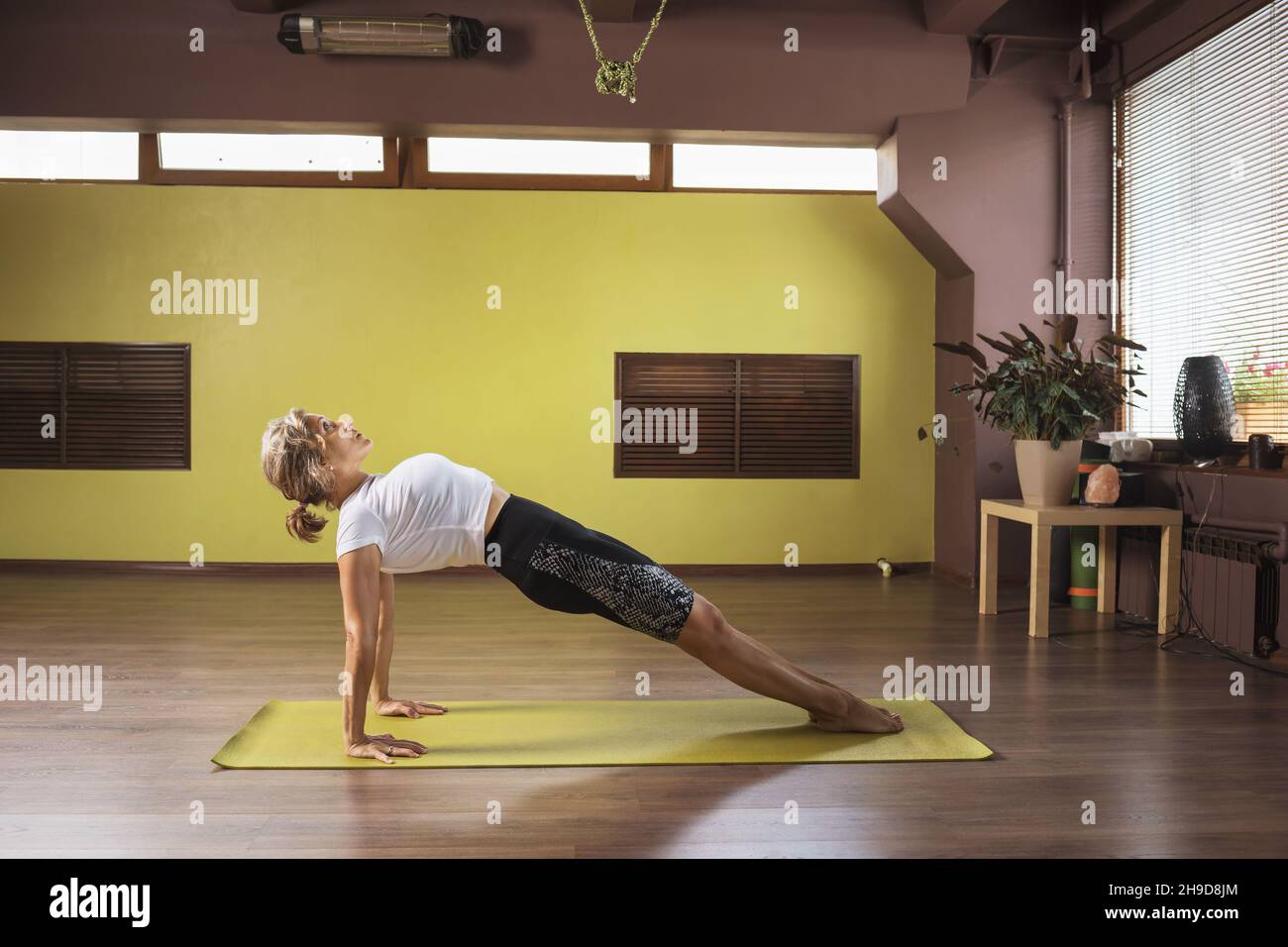 A woman practicing yoga, performs the purvottanasana exercise, stands ...