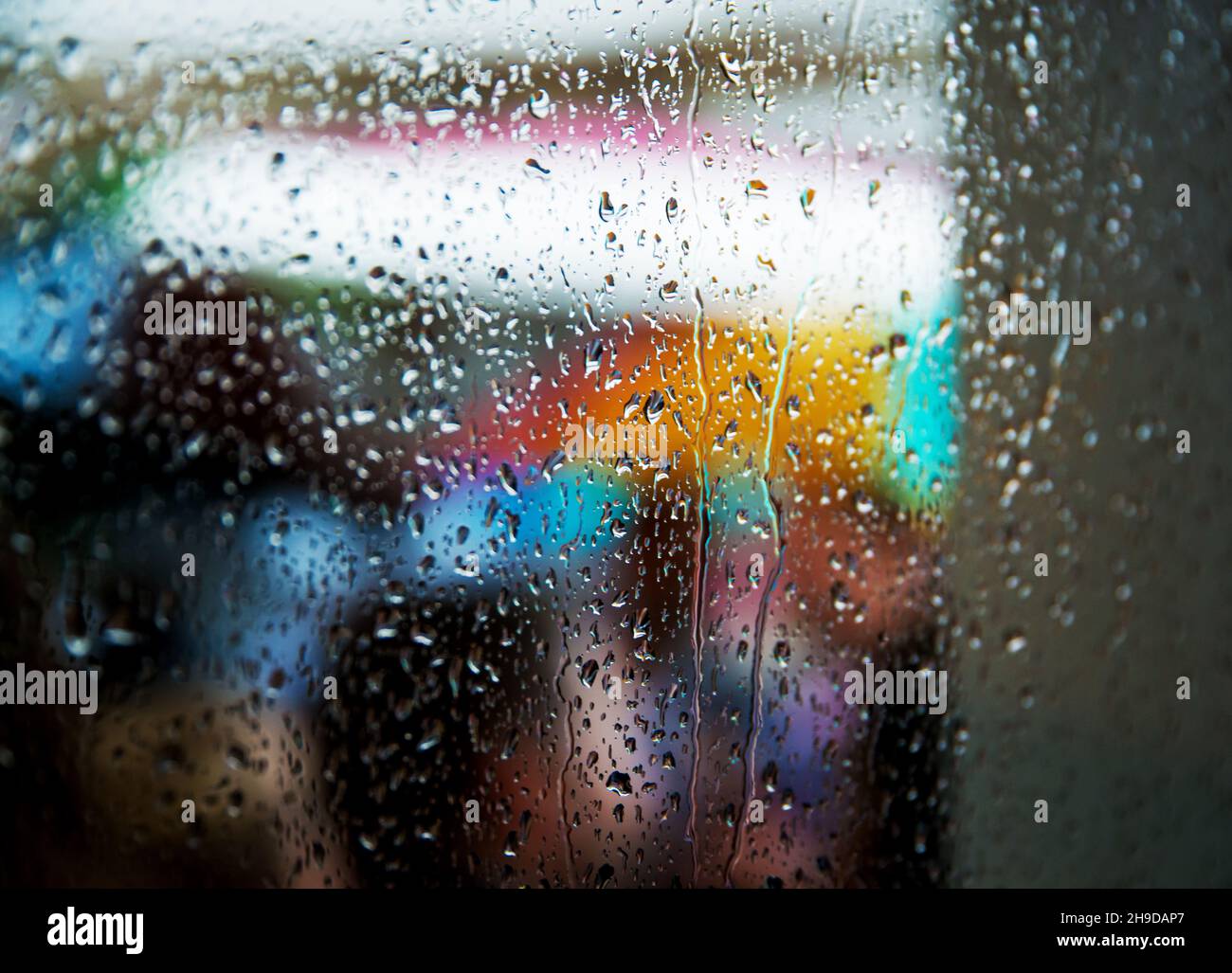 Drops of rain on a window pane, people in background. Shallow depth of ...
