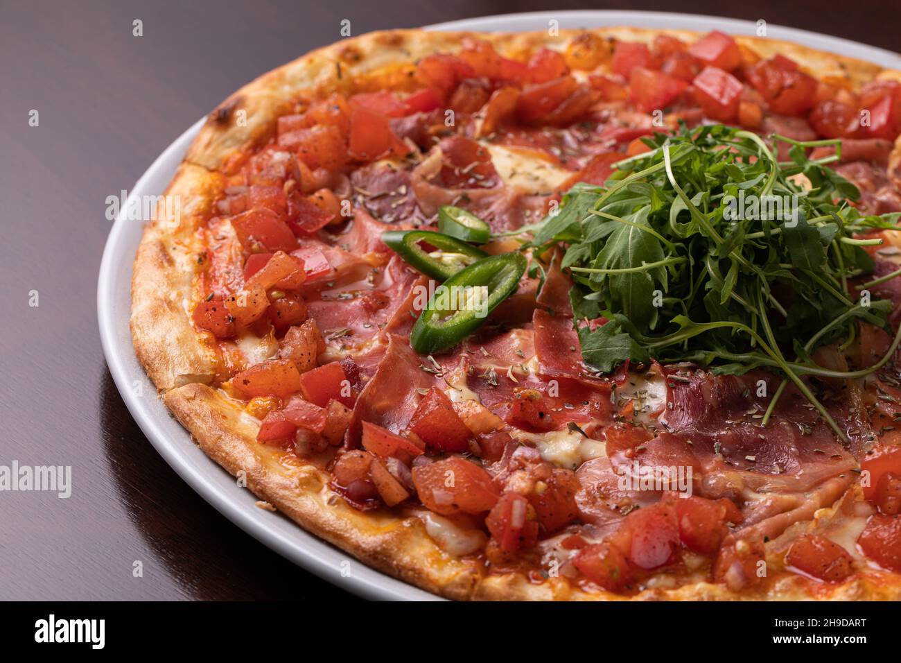 ham pizza with tomatoes, cheese and topped with green chili peppers and ...