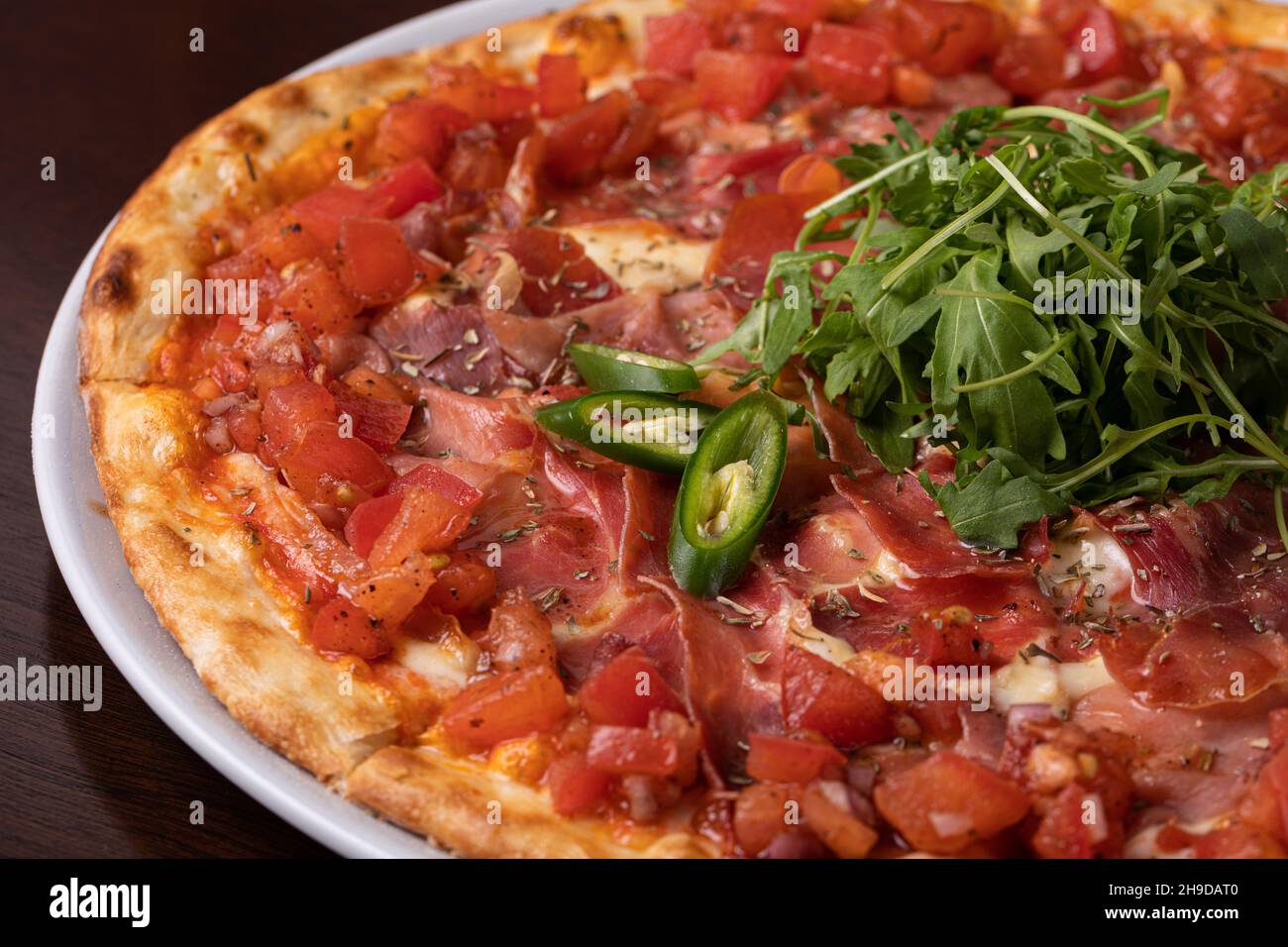 ham pizza with tomatoes, cheese and topped with green chili peppers and ...