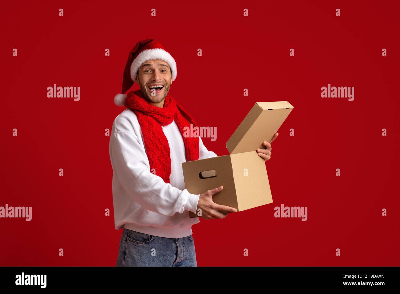 Christmas Delivery. Surprised Young Guy In Santa Hat Opening Parcel Box ...