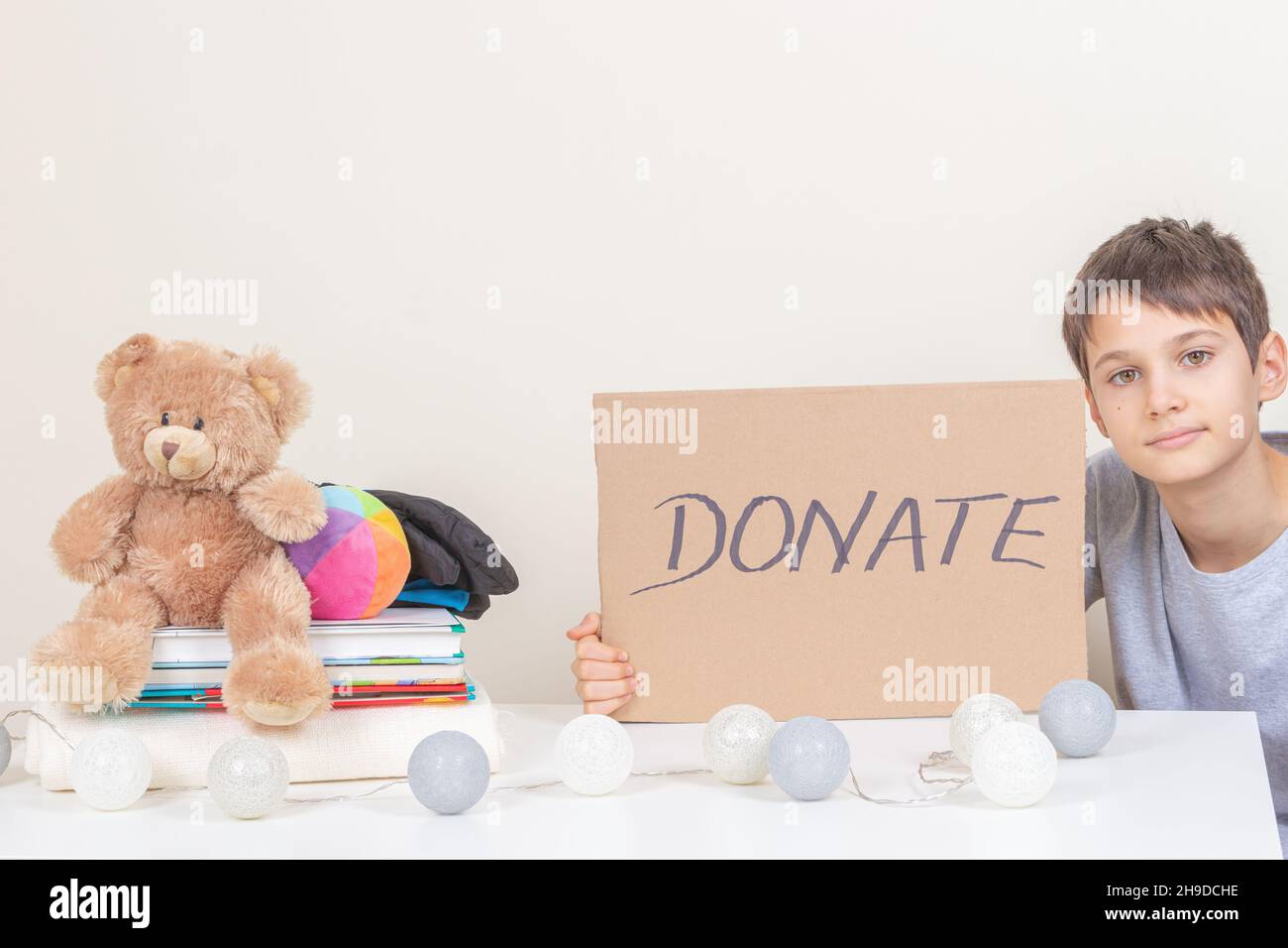 Charity, donation. Smiling kid holding brown piece of cardboard with ...