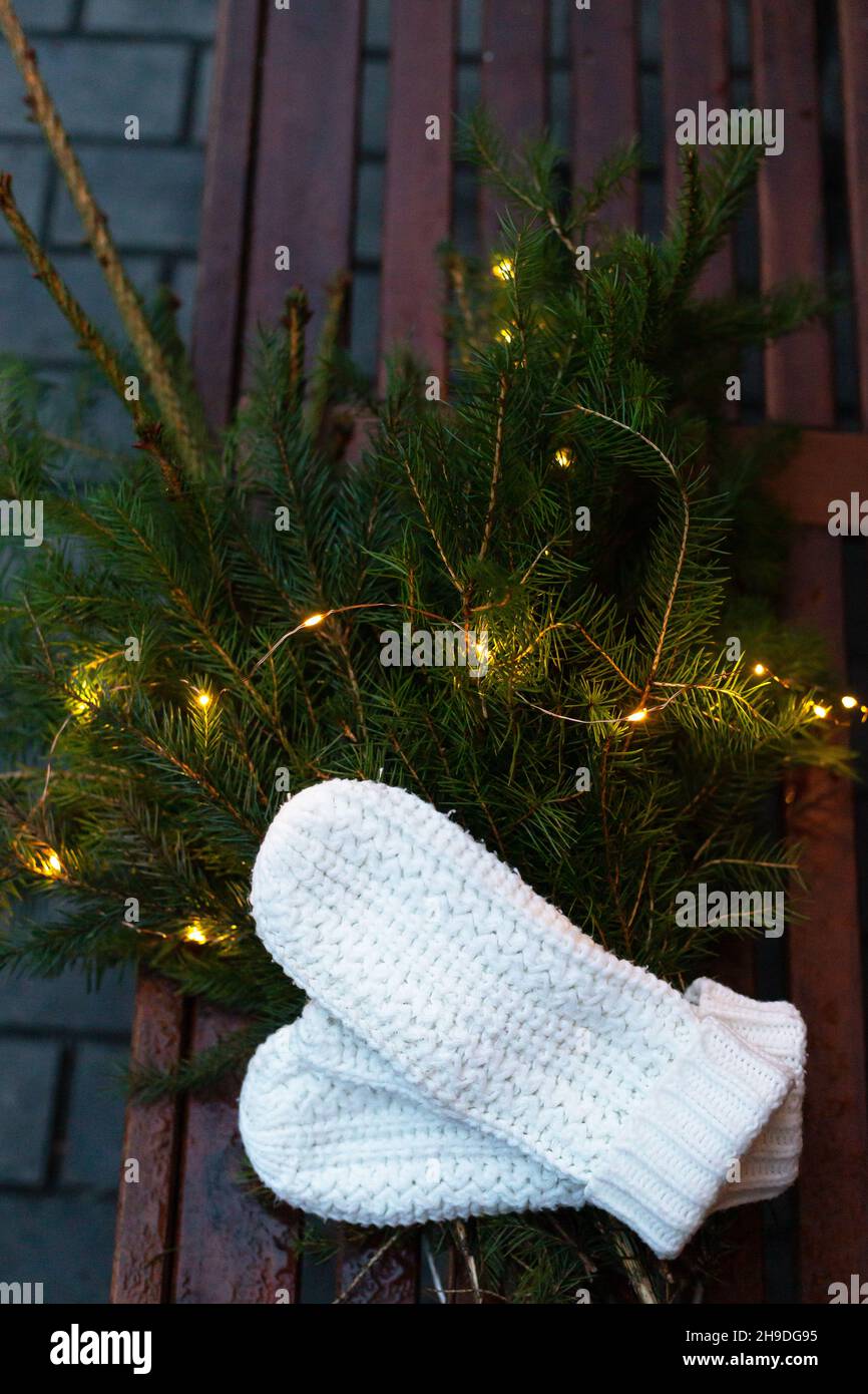 Branches of a coniferous tree decorated with a garland lie on a bench ...