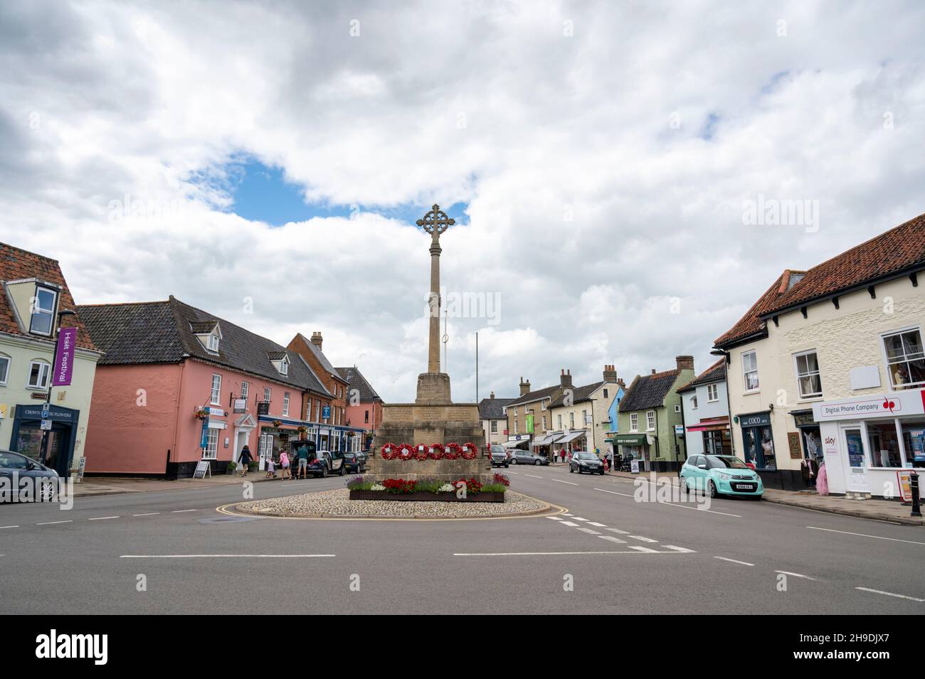 The main high street with the war memorial, shops, and parked cars in ...