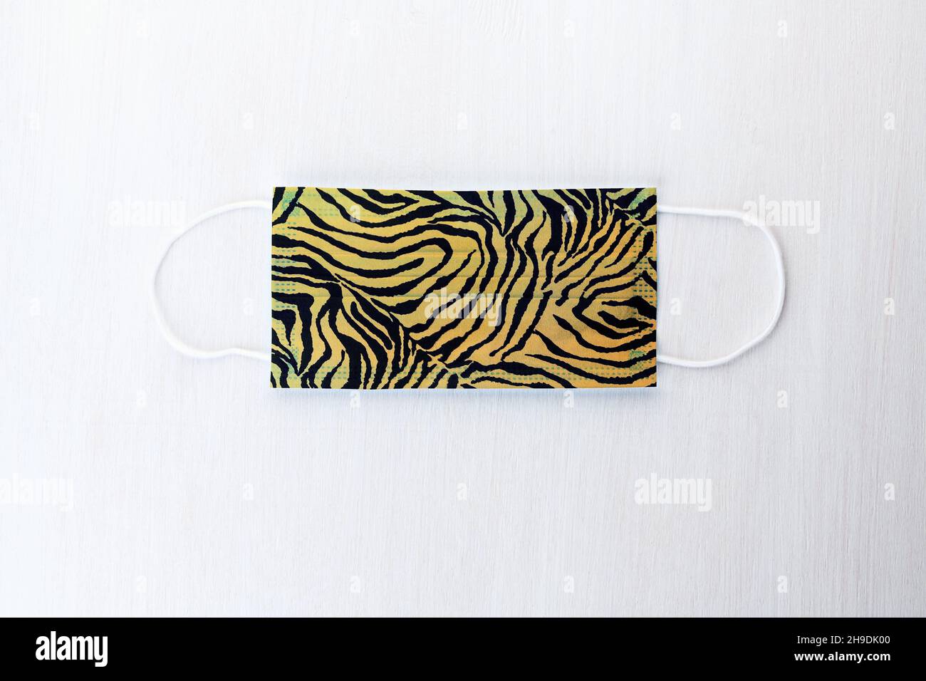 Tiger print medical mask on white wooden background. Coronavirus ...