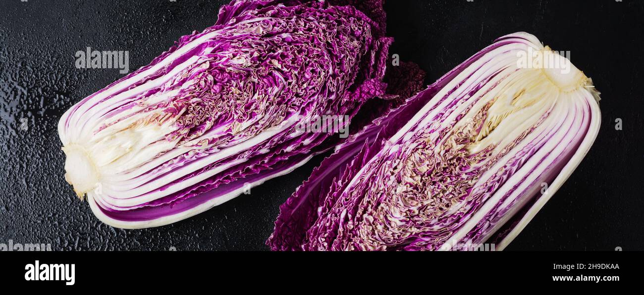 Fresh raw purple Chinese cabbage cut in half on a black concrete old ...