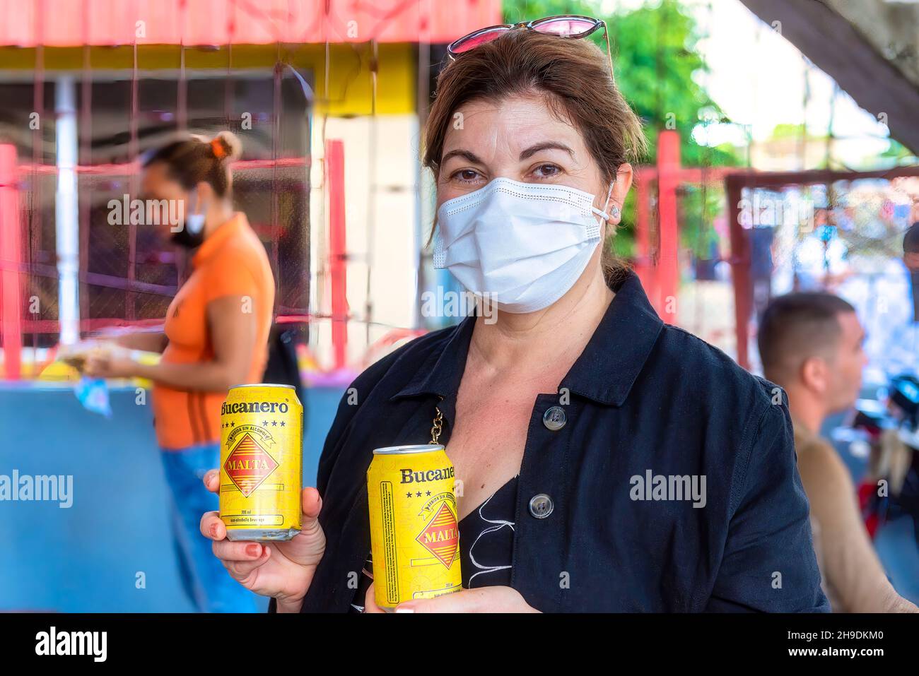 A Cuban woman showing cans of Bucanero Malta which are priced at a ...