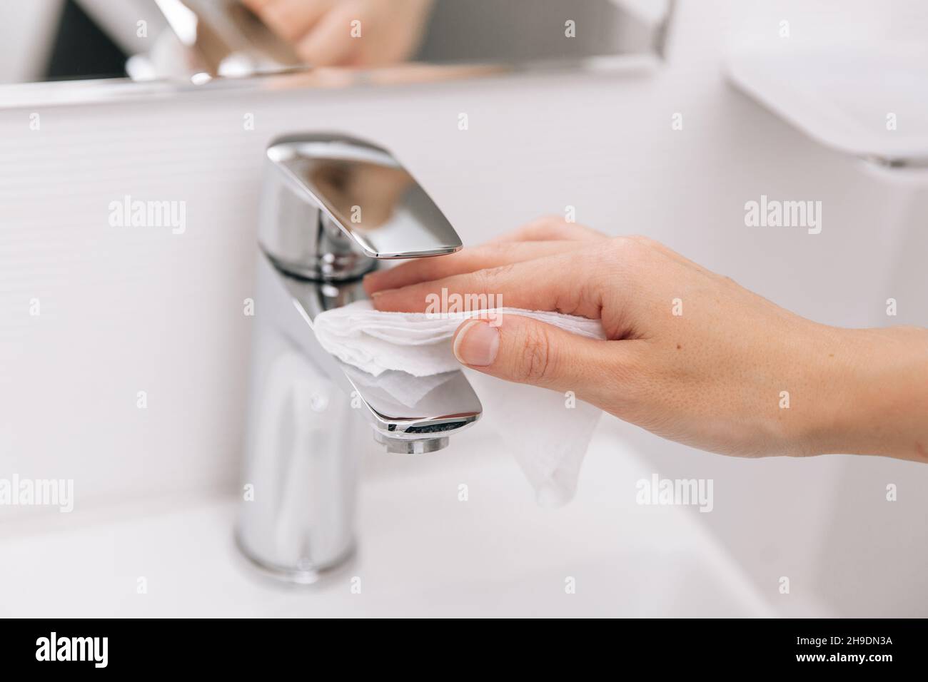 Cleaning the sink faucet with a microfiber cloth. Sanitize surfaces ...