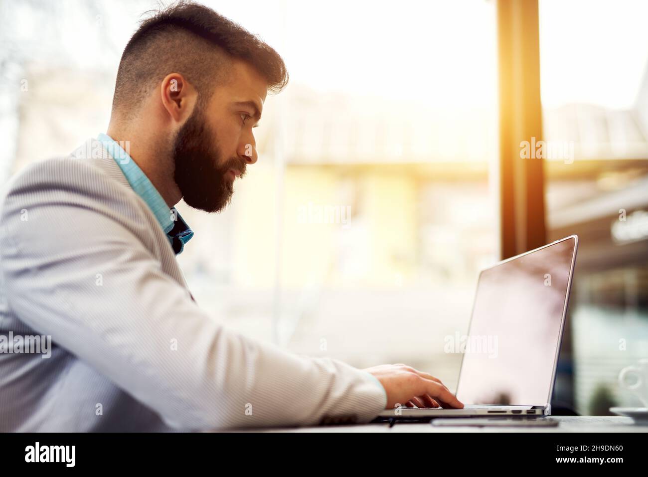 Side view of handsome man working on laptop in modern office with ...