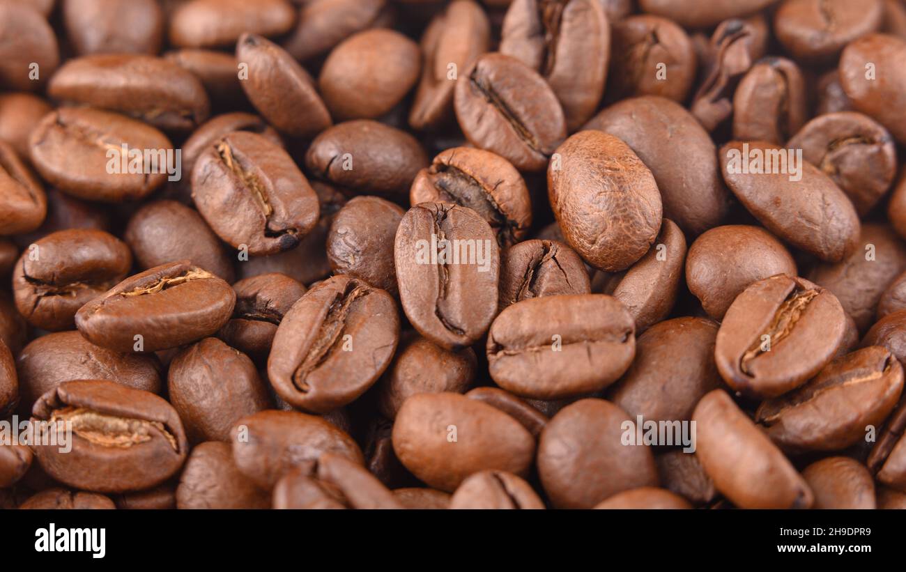The photo shows grains of roasted coffee. The textures of the coffee ...
