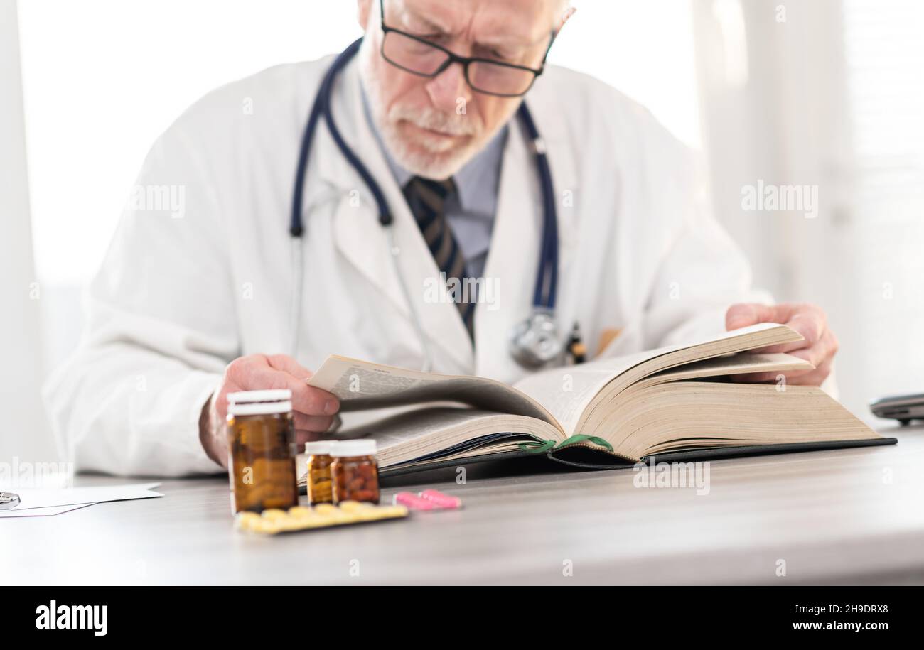 Senior doctor reading a textbook in medical office Stock Photo - Alamy