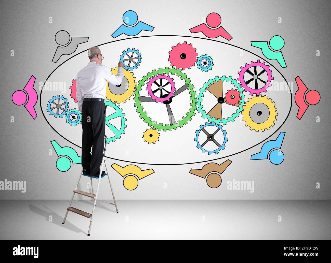 Man on a ladder drawing teamwork concept on a wall Stock Photo - Alamy
