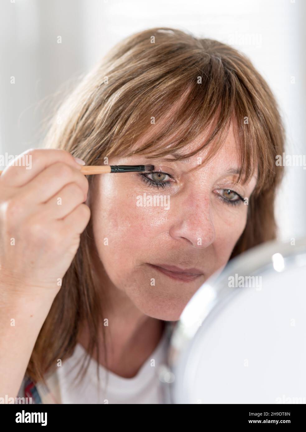 Mature woman applying eyeshadow powder Stock Photo - Alamy