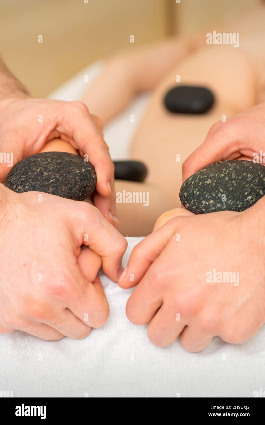Two Masseurs Make A Foot Massage With A Hot Stone In Four Hands At The