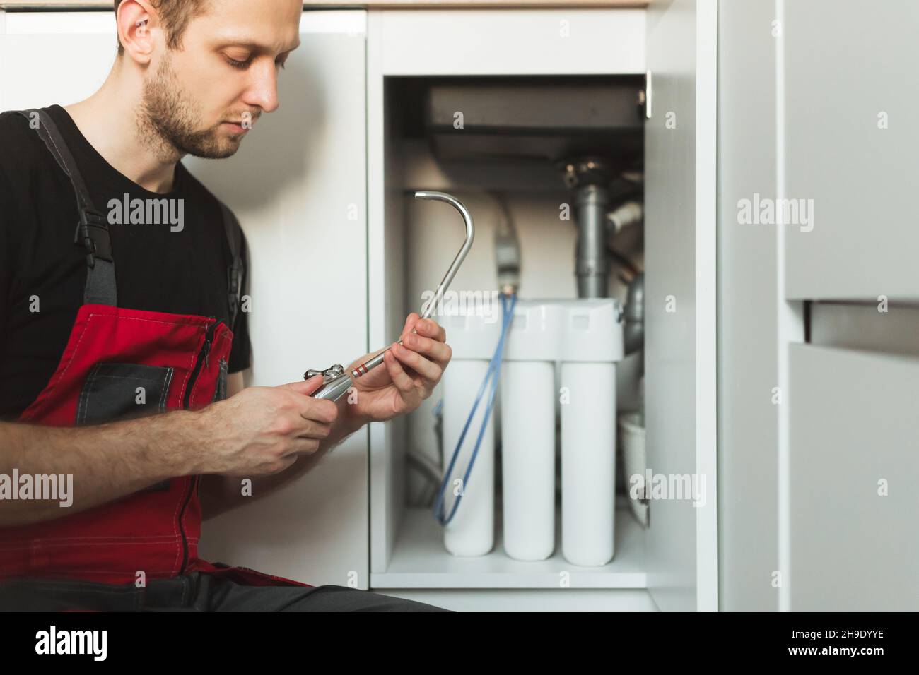 Plumber in the kitchen installs tap for household water purification ...