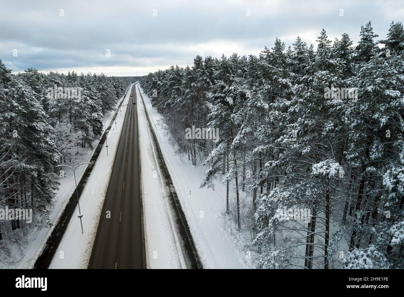 Aerial view of asphalt highway leading through frosty winter forests ...