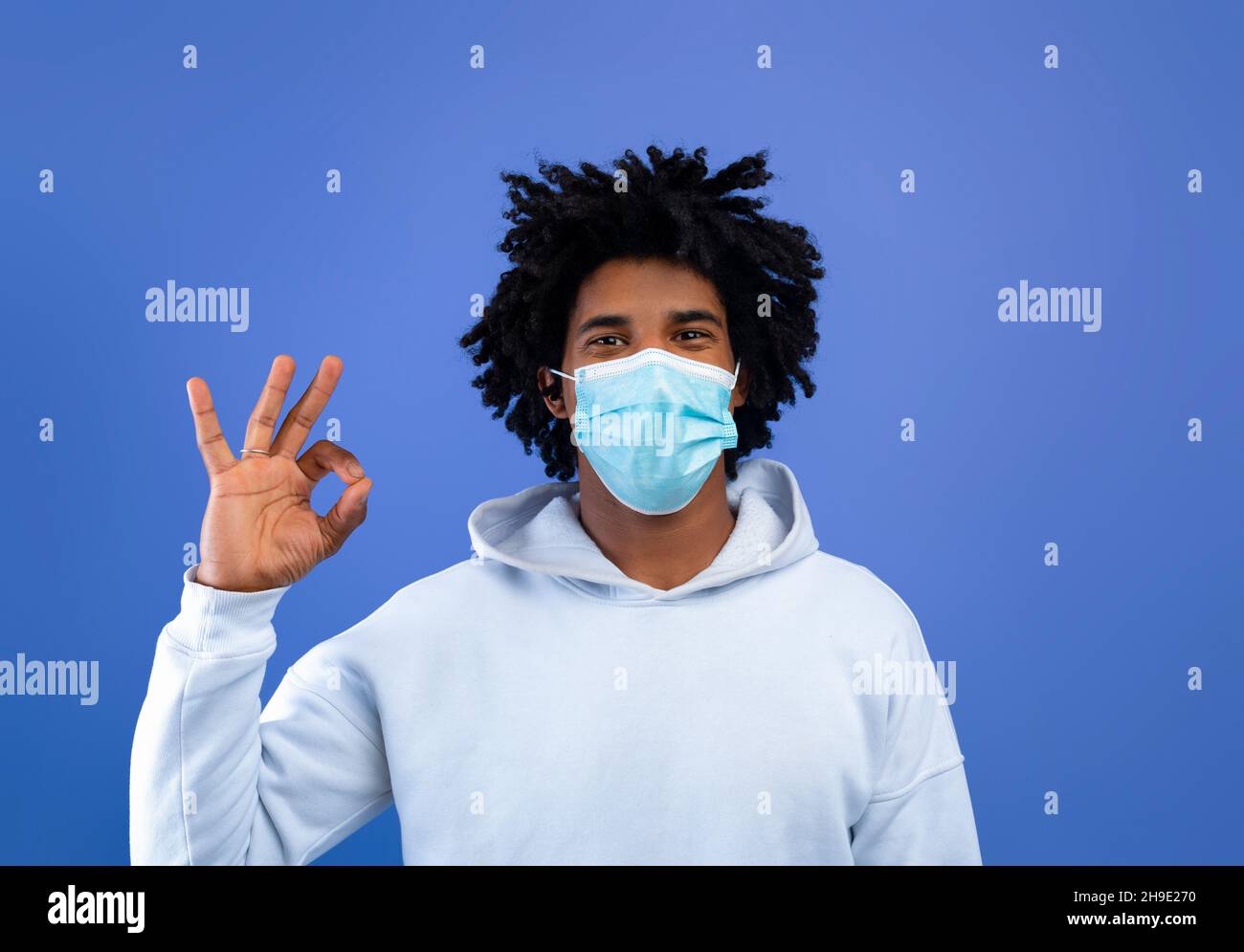 Funky black teen guy wearing face mask, gesturing OKAY, approving ...