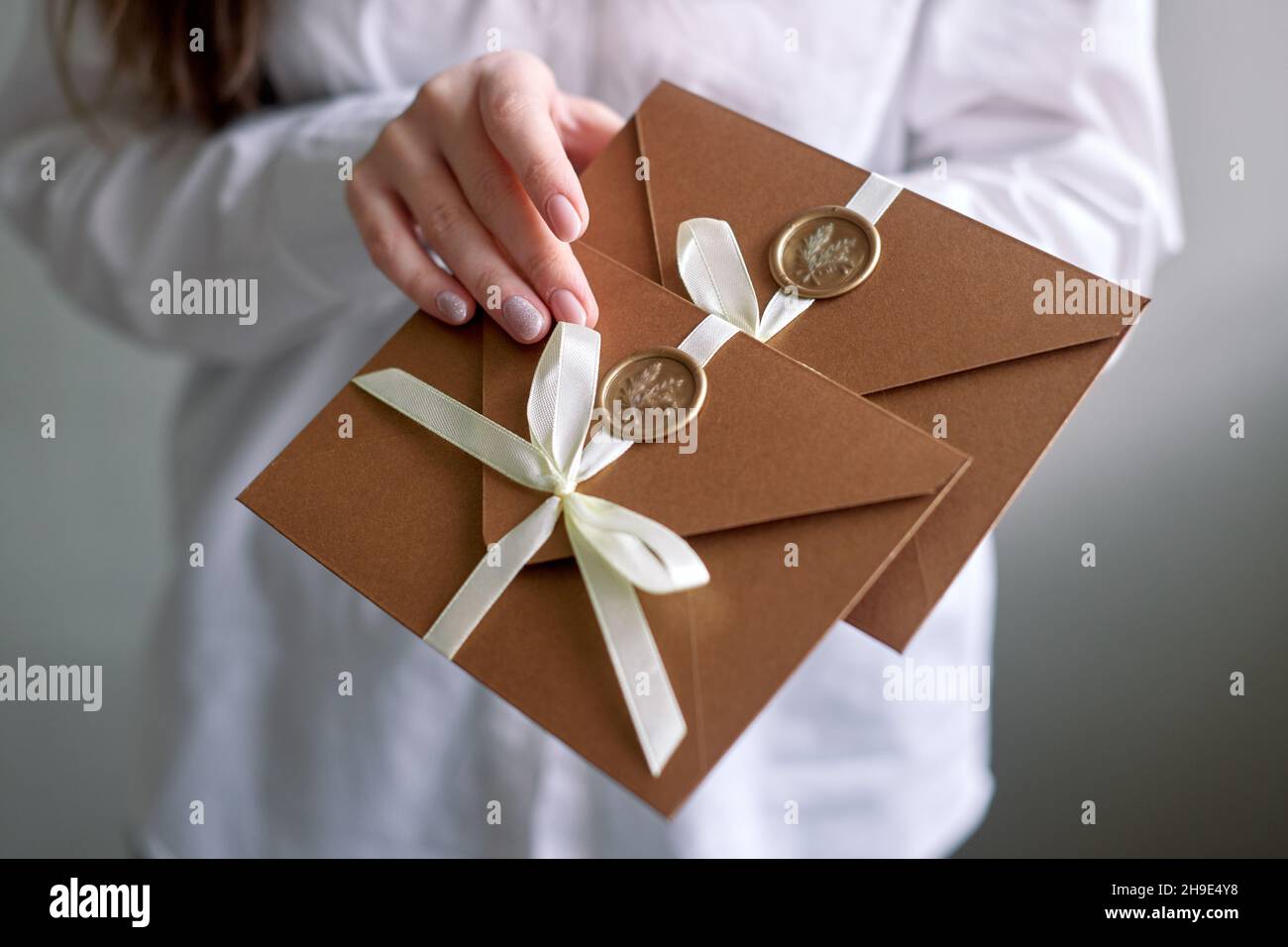 woman hold sealed envelopes. invitation envelope with ribbon and wax seal, gift certificate ...