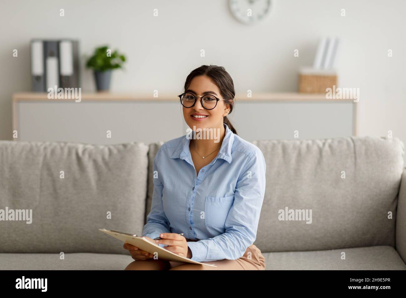 Cheerful arab female psychologist writing in clipboard, having session ...
