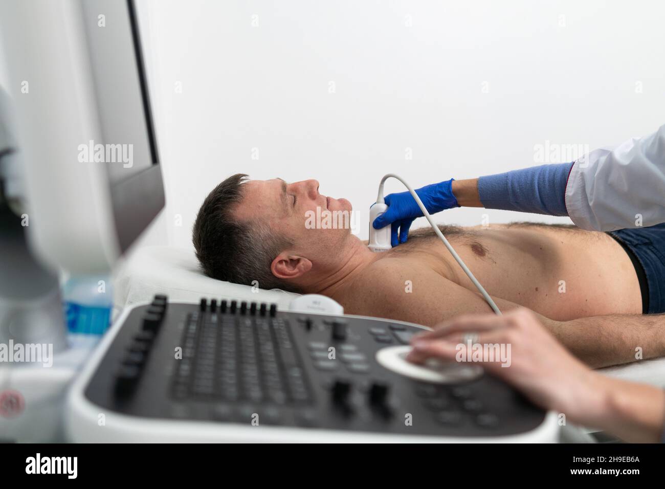 Doctor using ultrasound machine to scan heart of a male patient ...