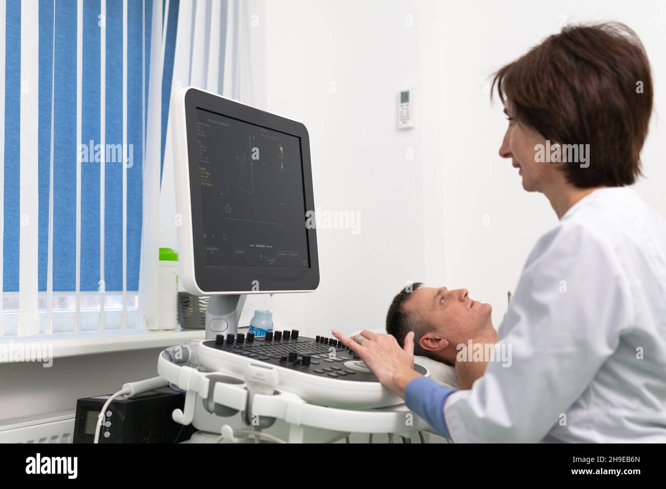 Doctor using ultrasound machine to scan heart of a male patient ...